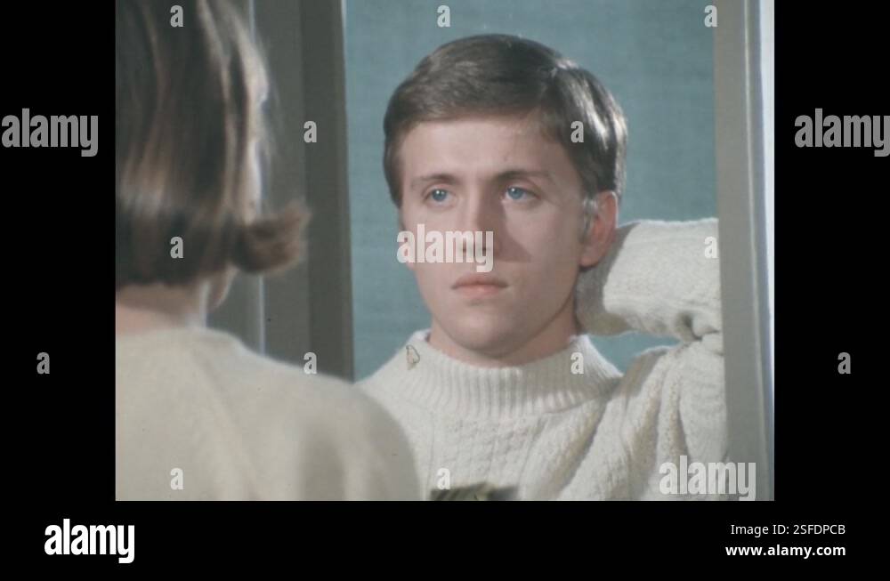 1950s: Man holds up film slate. Teen boy stands in front of teen girl ...