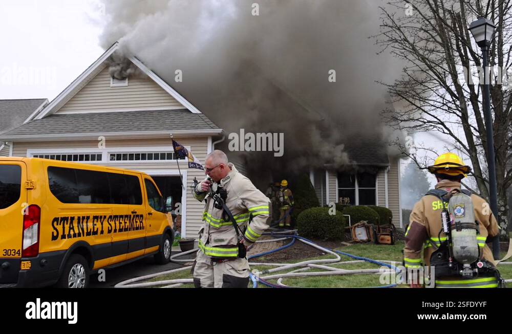 A Group of Firefighters Working Quickly to Fight a House Fire Taking ...