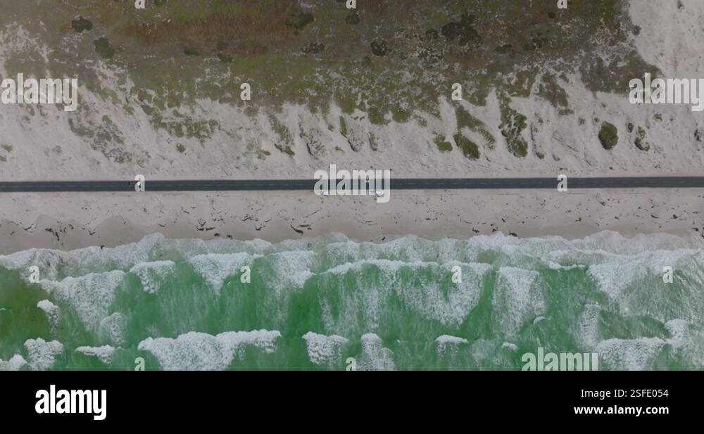 Top down horizontally panning footage of straight coastal road passing ...