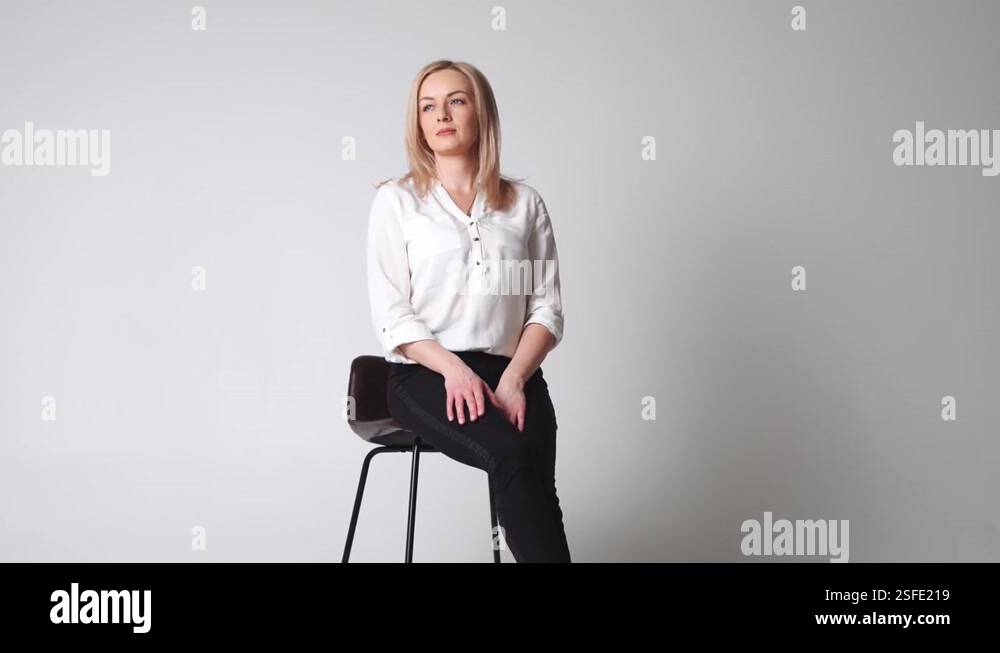 Caucasian woman in corporate wear sitting on chair on white background ...