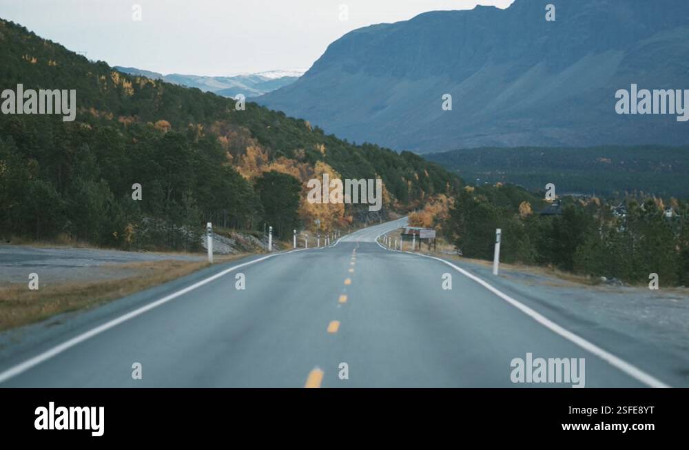 Narrow two-lane road snaking along the fjord. A small village on the ...