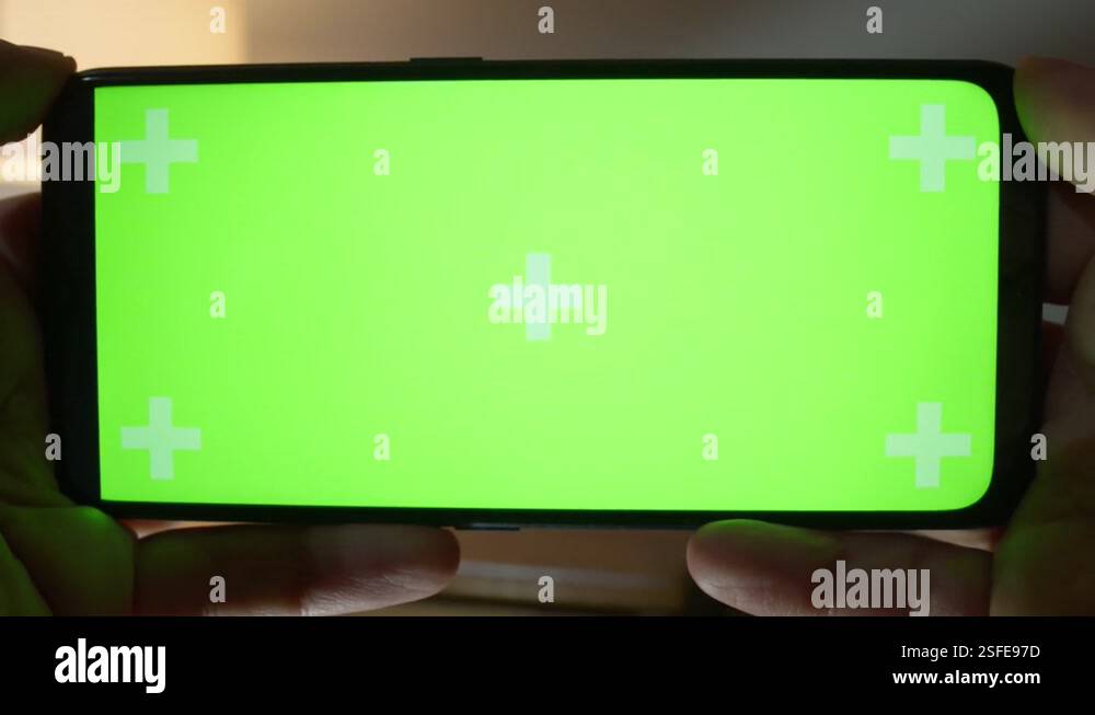 Man using a smartphone in horizontal mode with a Green screen layout ...