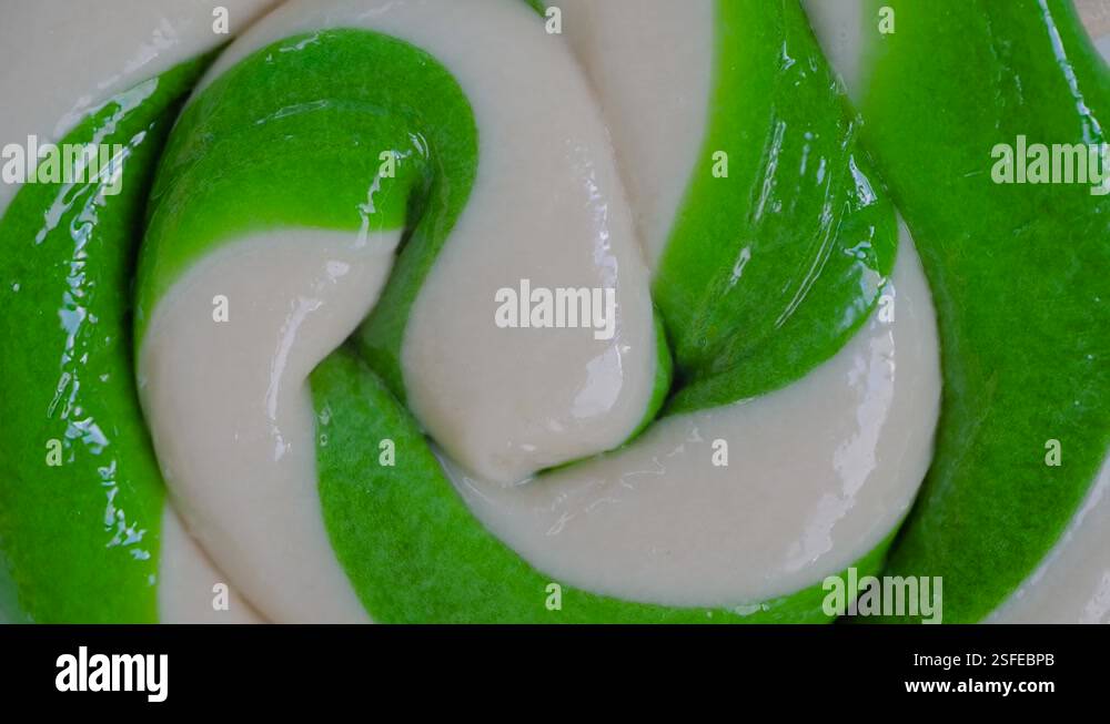 Green and white large spiral candy lollipop on rotating surface - close ...