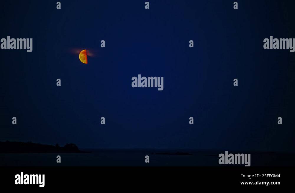 Timelapse on a clear blue night of half moon going up the night sky ...