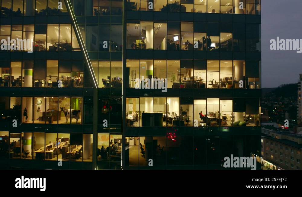 Cinematic shot from a drone at the windows of a skyscraper at night ...