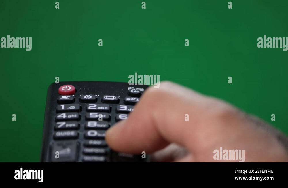 Male hand with TV remote pressing button switch channels on green ...
