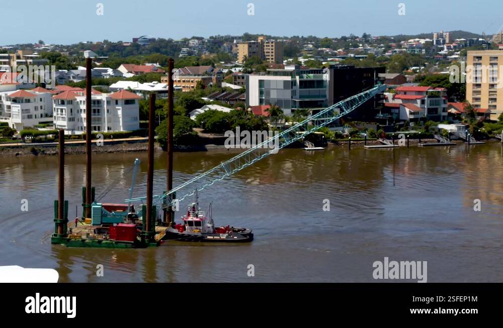 A tug boat works hard, in the current to manoeuvre a floating barge ...