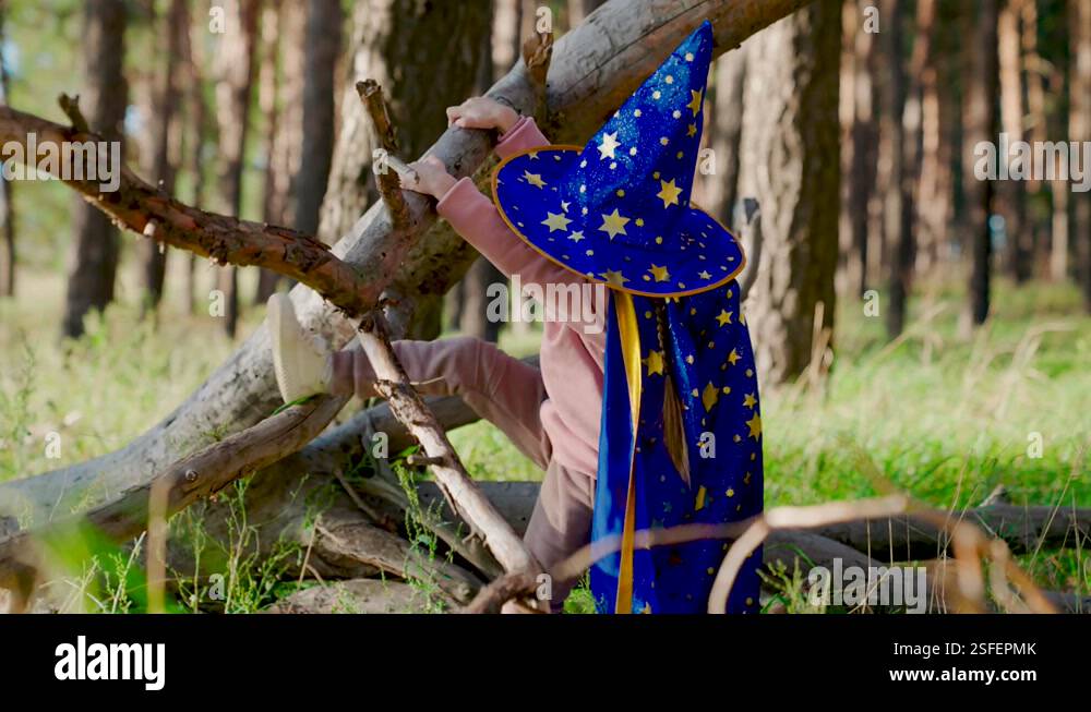Girl, kid, plays in wizard costume in spring in forest, studies dry ...