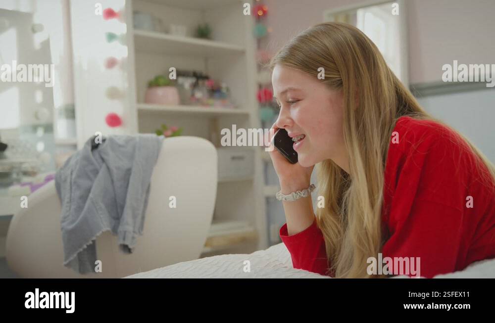 Teenage Girl Wearing Orthodontic Braces Lying On Bed At Home Talking On ...