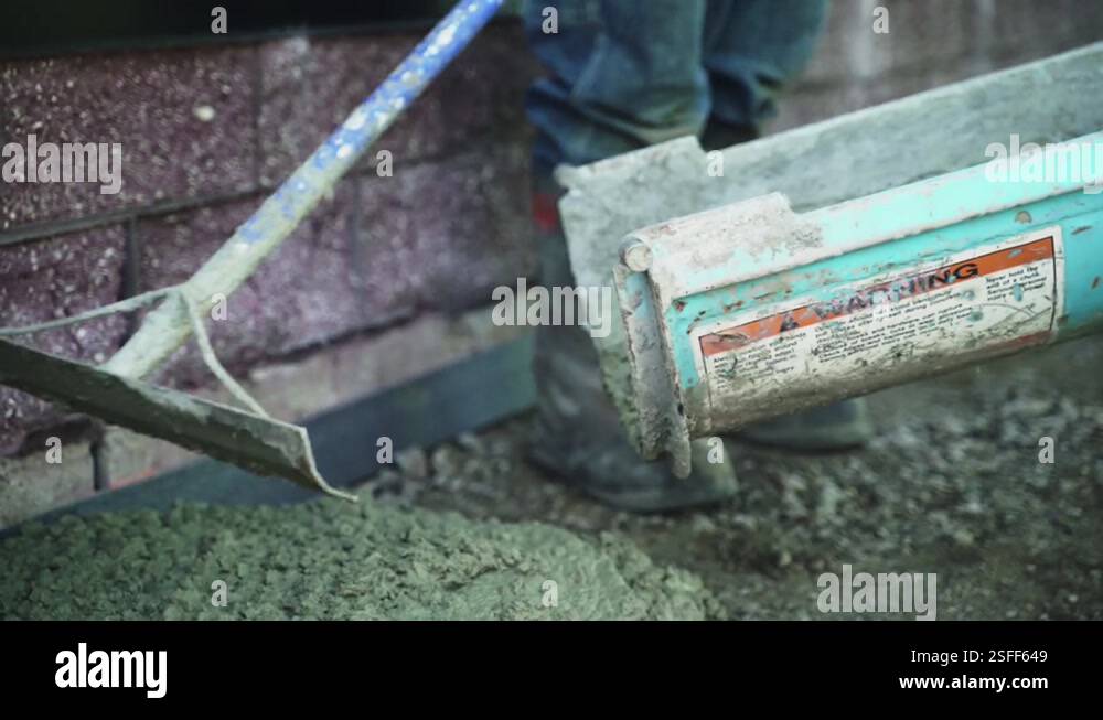Concrete cement pouring down chute, construction worker spreading it ...