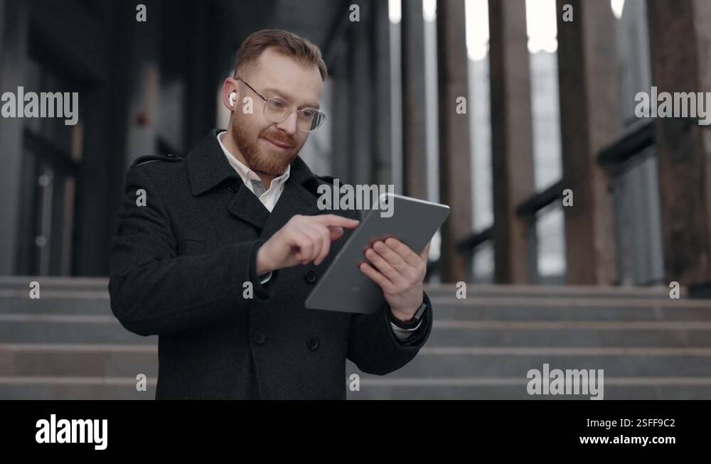 Businessman using tablet device at street. Man tapping and scrolling on ...