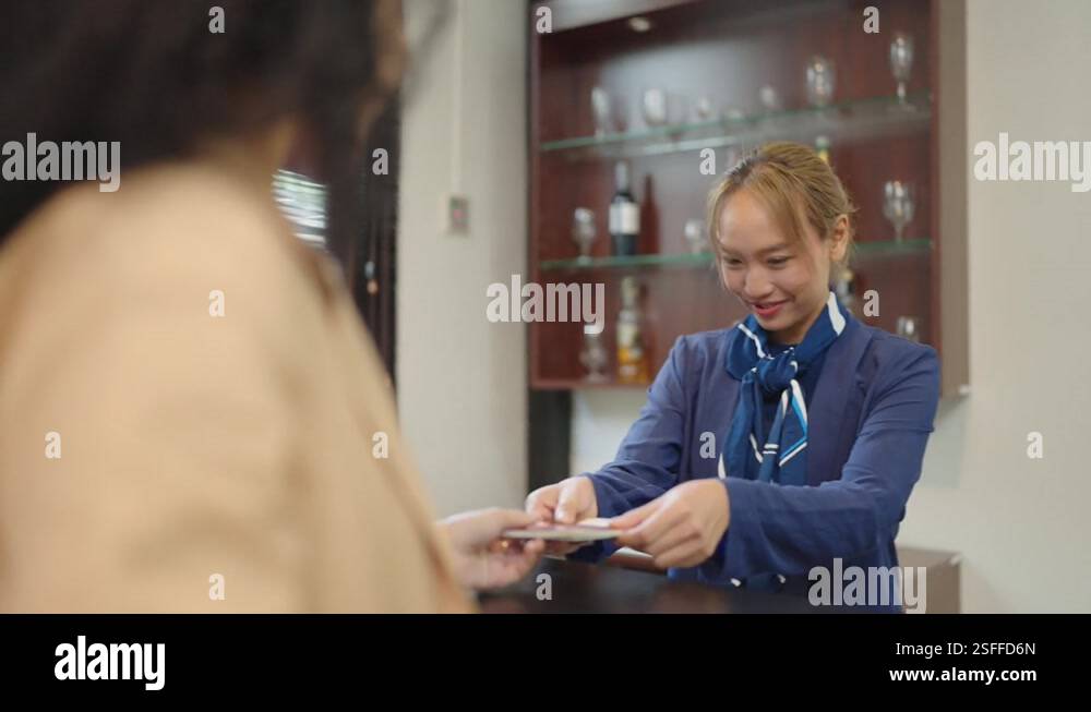 Friendly Asian concierge giving to African American guests their check ...