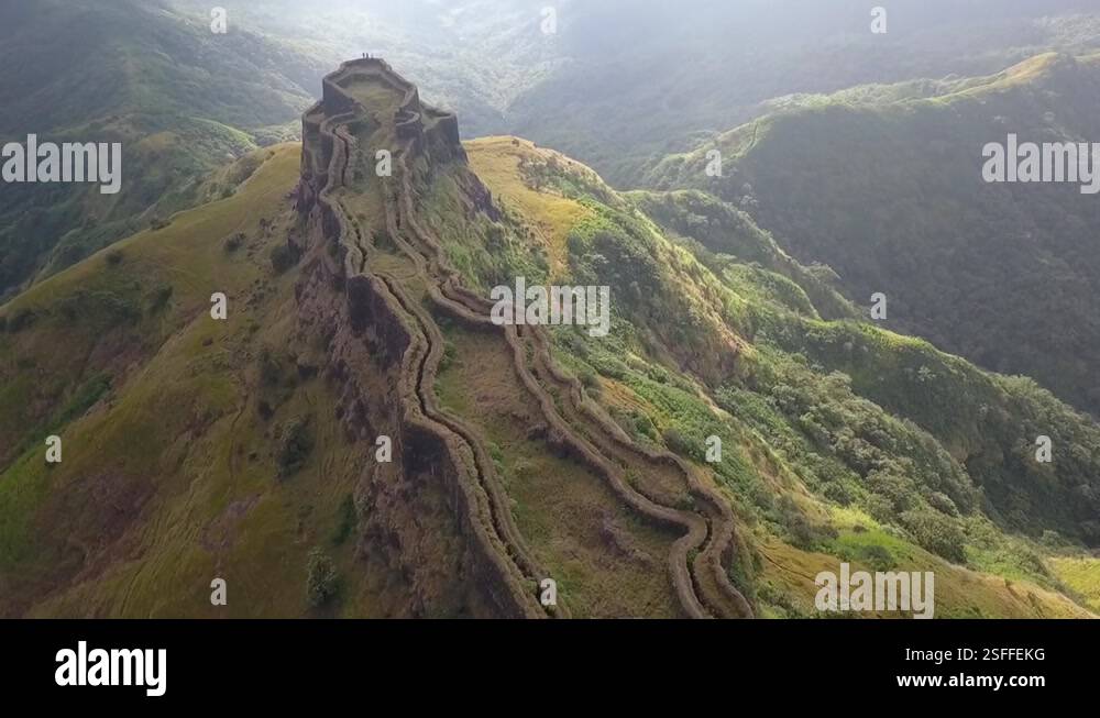Misty green aerial of Zunjar Machi grassy walls in Torna Fort, India ...