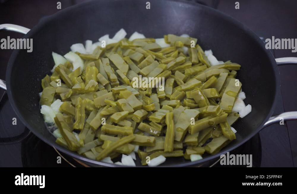 Cactus cacti food being sautéed with chopped onions in frying pan. A ...