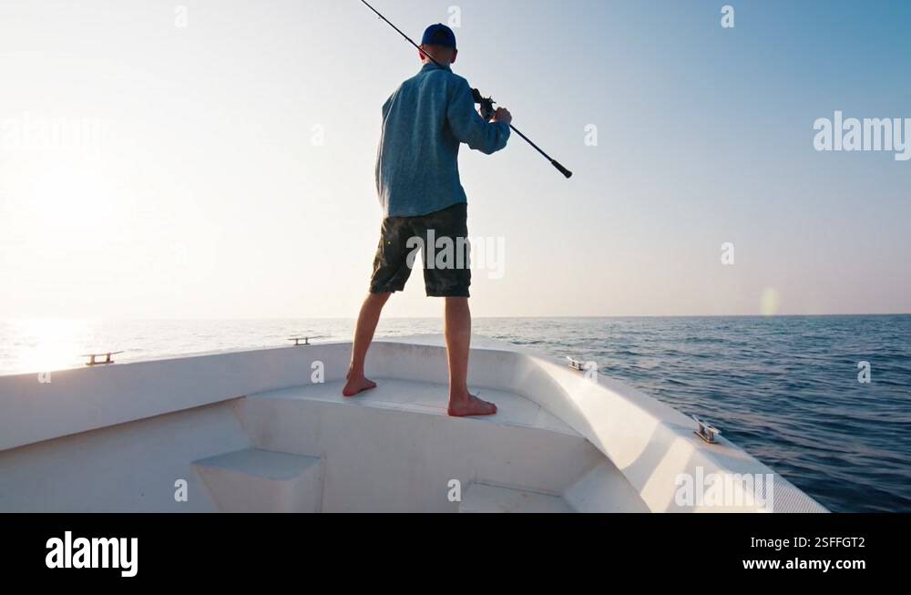 Open sea fishing. Angler stands with fishing rod on the boat floating ...