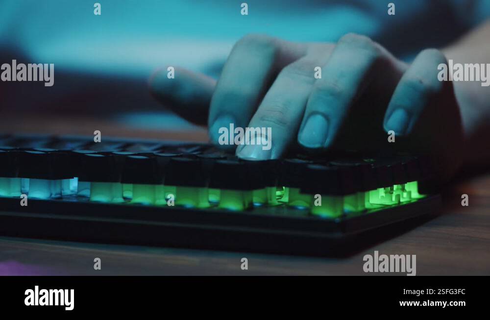 Gamer typing on backlight keyboard close-up, man playing video game ...