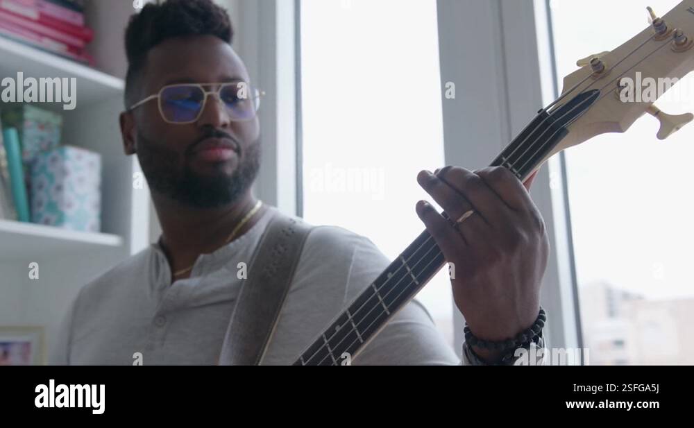 Close Up Pan Right Slow Motion of a Young Man Playing a Bass Guitar in ...