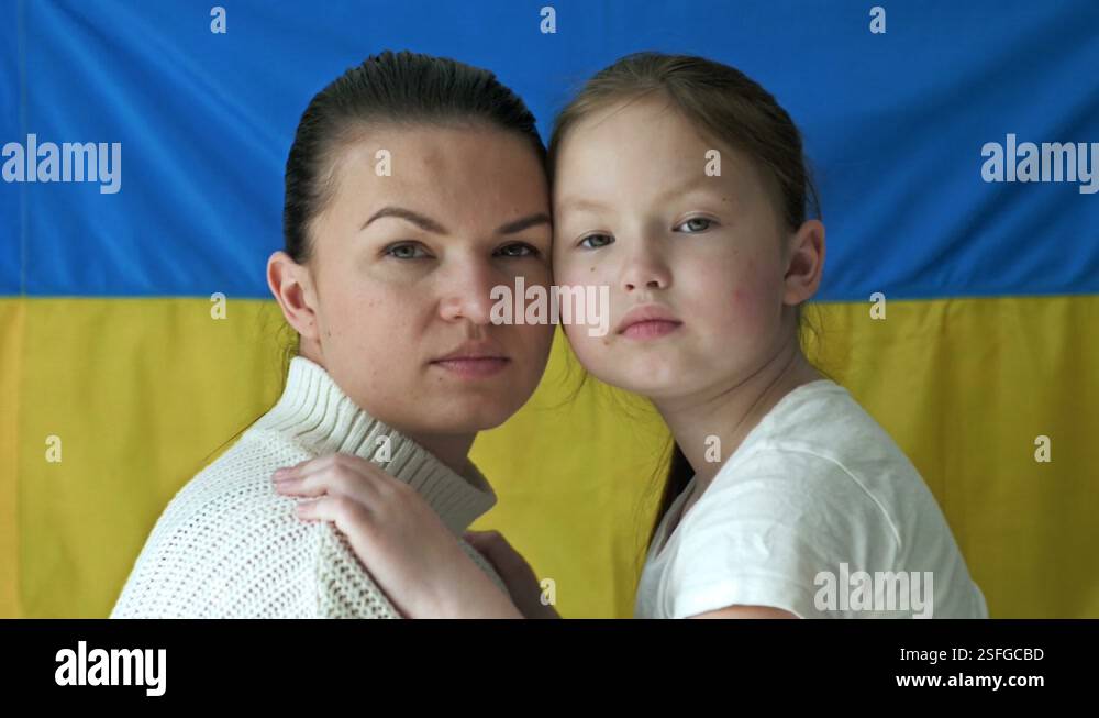 Young woman with her daughter on the background of the Flag of Ukraine ...