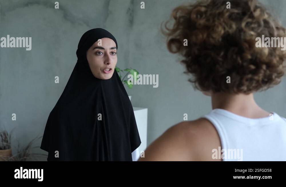 Two women are debating about religion. A Muslim woman in a black hijab ...