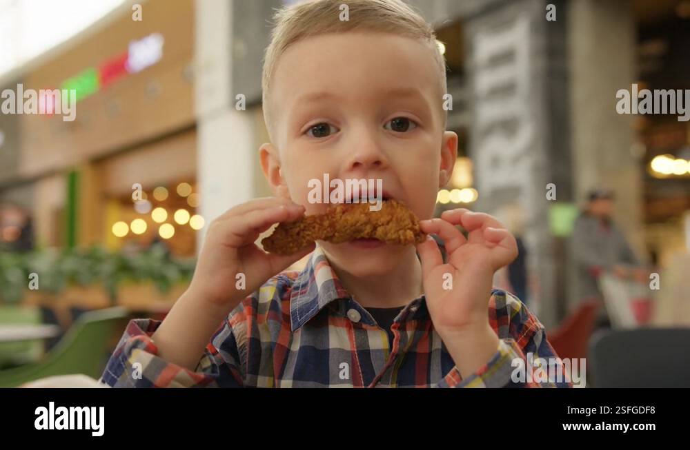 Caucasian kid satisfies his hunger eating deep-fried chicken from fast ...