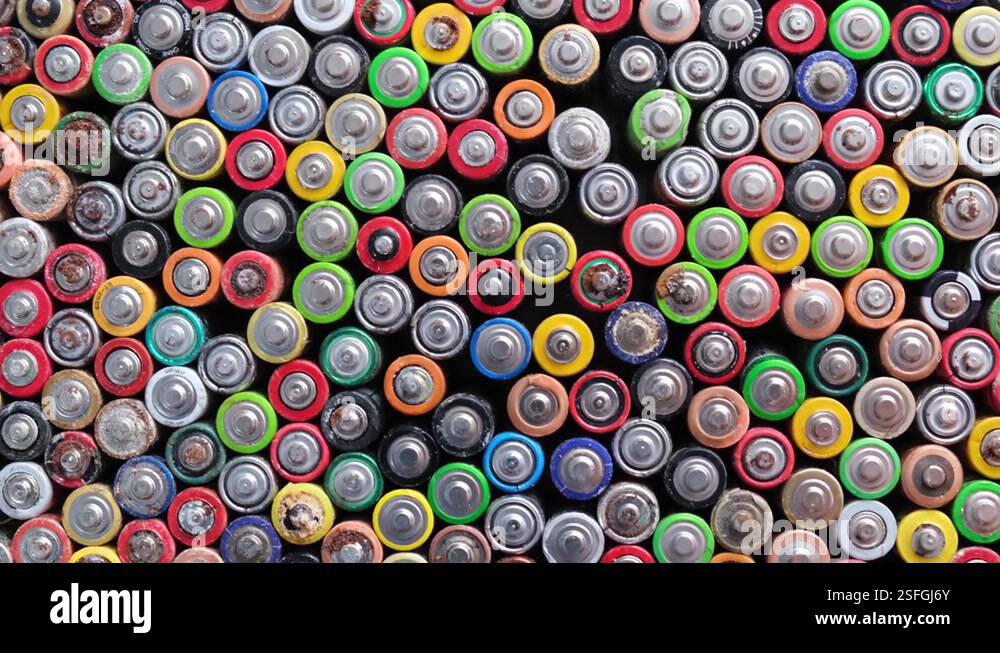 Different types of used batteries in a heap, top view. Alkaline AA ...