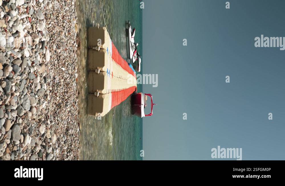 Floating plastic pontoon on pebble beach with moored jet bikes ...
