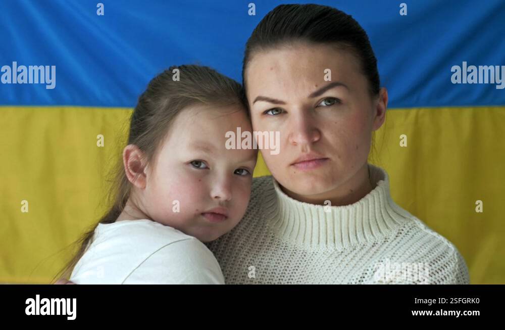 Young woman with her daughter on the background of the Flag of Ukraine ...
