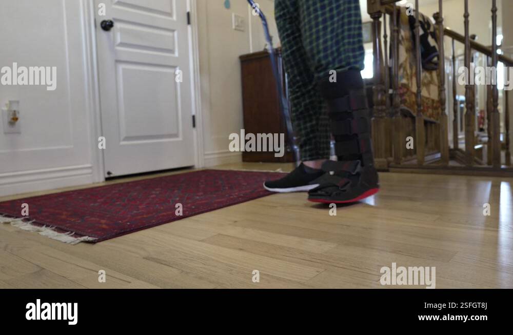 Man with ankle injury wearing an orthopedic boot and using a cane to ...
