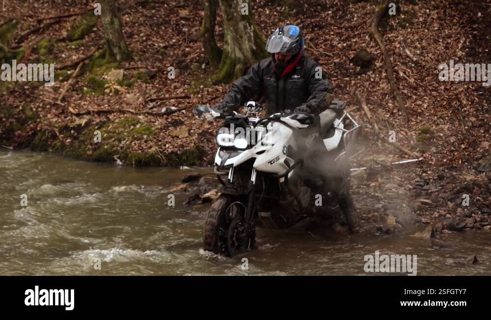 Off-Road motorcycle crossing the river splashing water and dirty mud ...