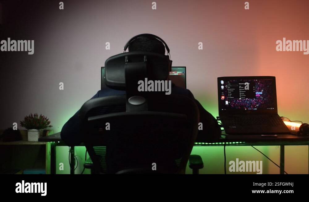 Gamer playing video games on his computer. RGB gaming room setup Stock ...