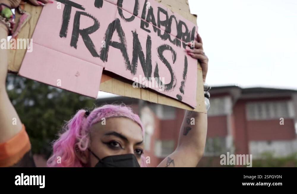 A trans woman is holding up a sign in protest of the violence against ...