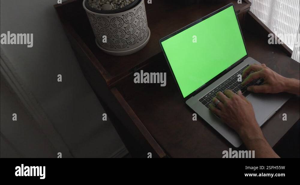 Employee working from home types at desk with a laptop. Computer screen ...