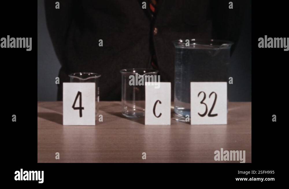 1960s: Glass beakers, two empty, one full of water, numbers, symbols ...
