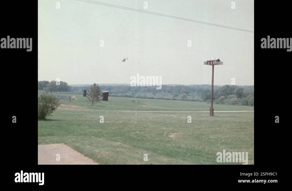 1950s: Helicopter hovering above grassy landscape. Aircraft flying over ...