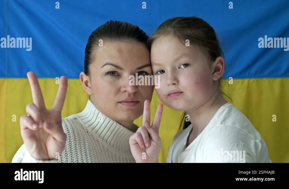 Young woman with her daughter on the background of the Flag of Ukraine ...