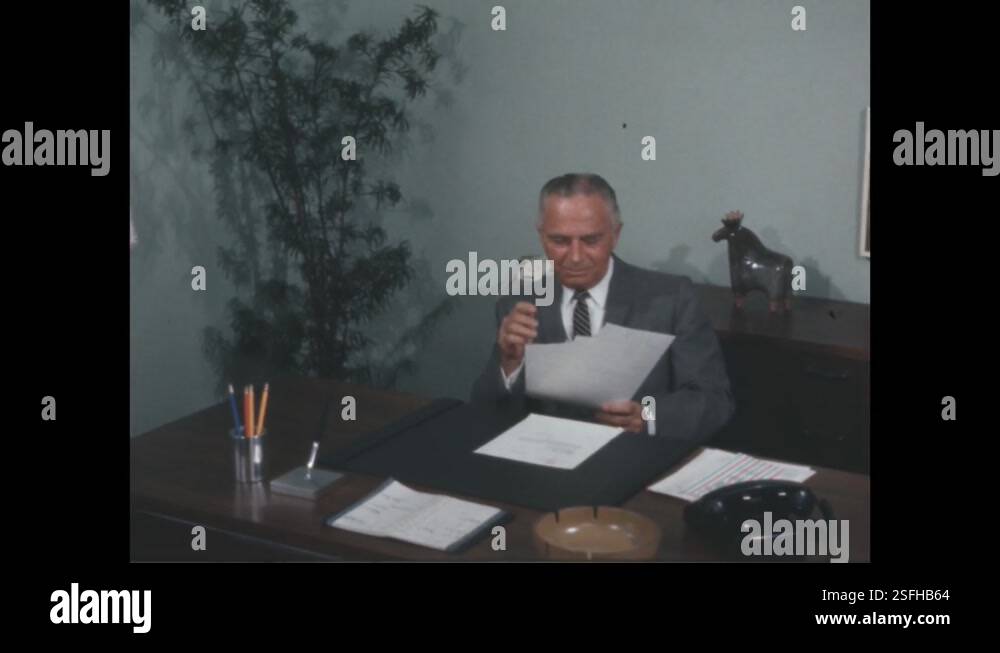 1960s: Slate. Man in a suit sits at a desk. Woman enters with a steno ...