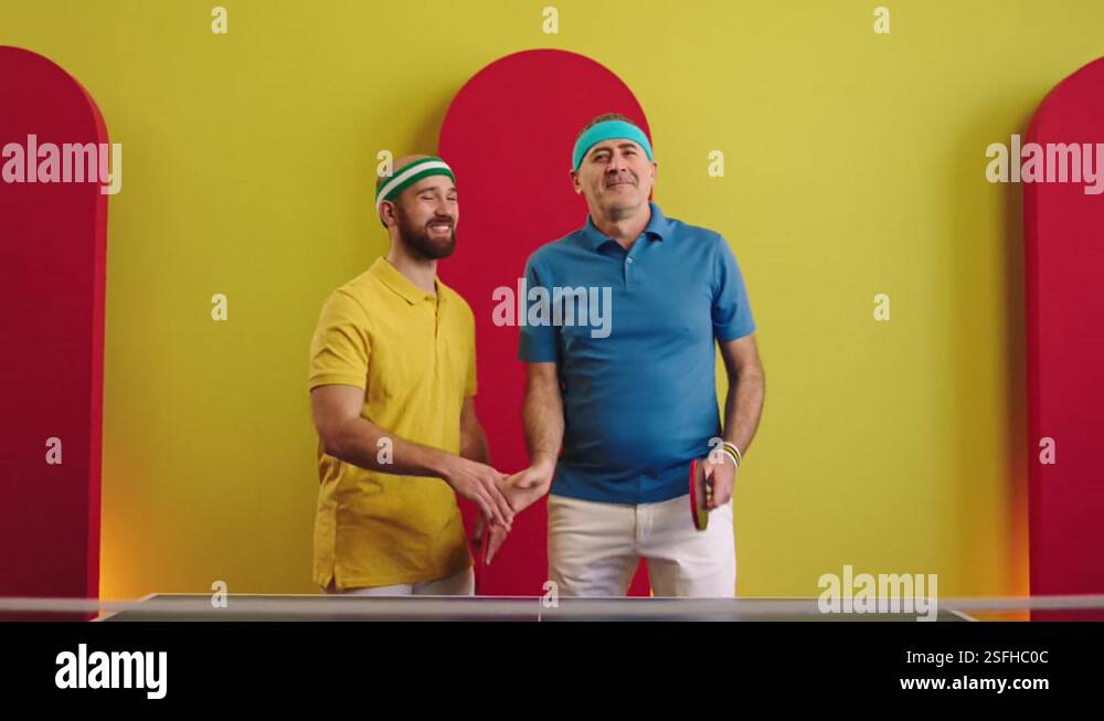 Two ping pong players very charismatic old and young men shaking hands ...