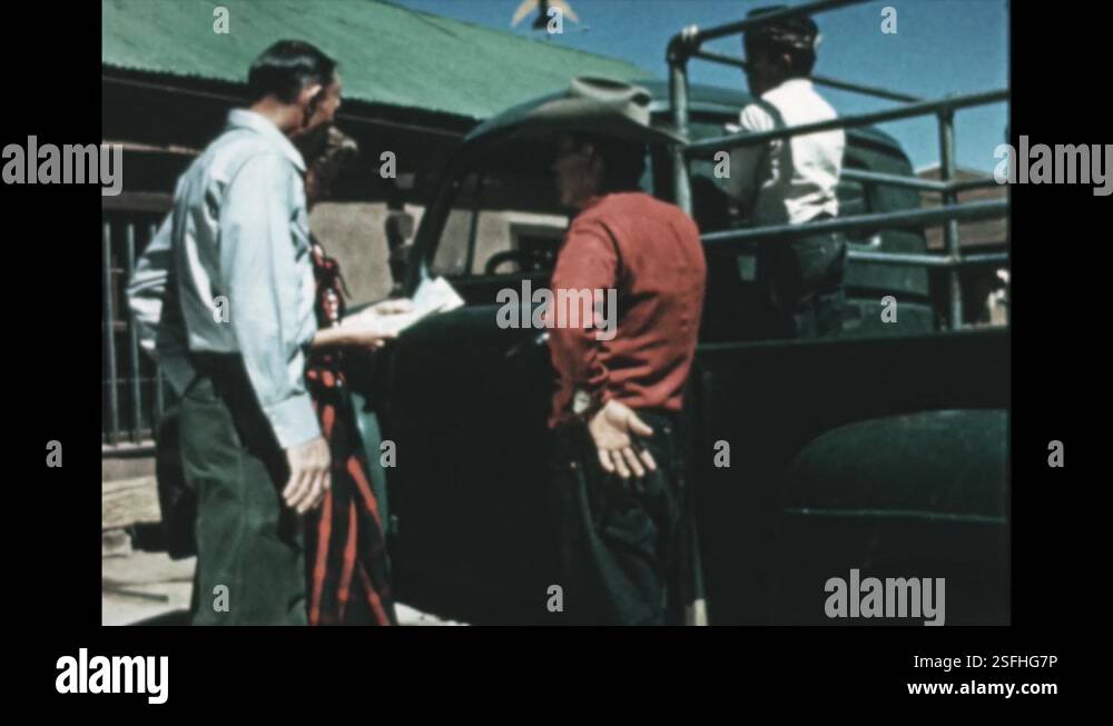 1950s: Boy stands in pickup truck bed, smiles, looks proud. Man, woman ...