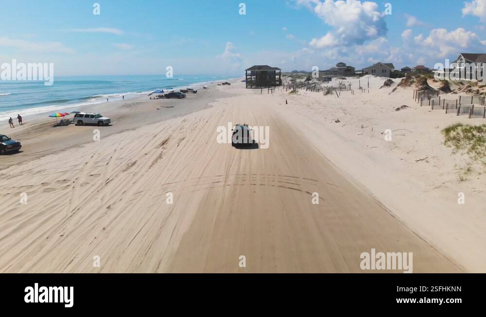 Drone following black suv on Outer Banks Corolla 4x4 beach, houses can ...