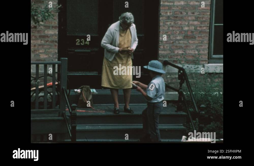 1970s: City building stoop, boy wears postal service uniform, hands ...