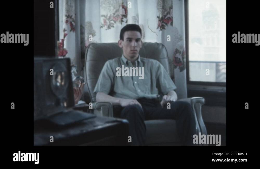 1960s: hand claps clapper board in front of camera. Man sat in armchair ...