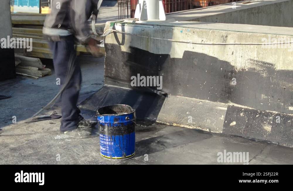Roofer installing roofing felt with heating and melting of bitumen roll ...