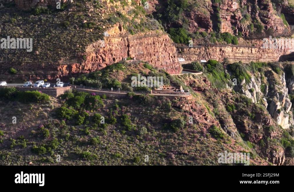 Cars pass people hiking Chapmans Peak scenic route on narrow curved ...