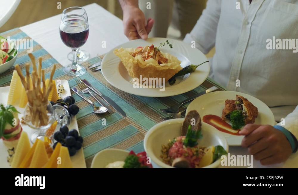 Waiter serving a plate of food to a man guest in a restaurant, cropped ...