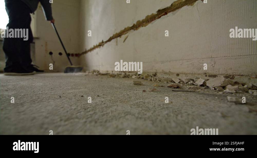 Static shot of sweeping rubble in an old abandoned building. Cleaning ...