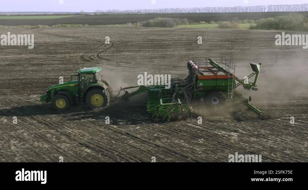 Tractor sowing seeds with seeder driller in field. Process of sowing ...