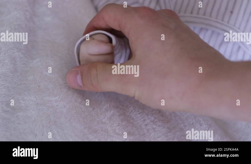 Man gently stroking baby's clenched fist. Neurological reflex, palmar ...