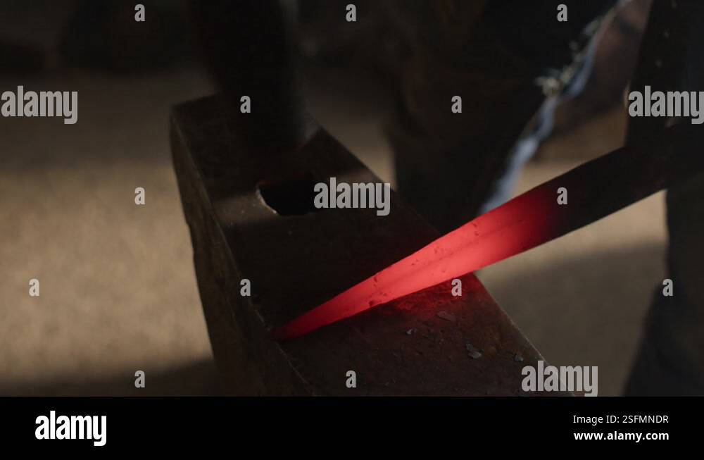 A man flattens an iron billet on an anvil with a hammer Stock Video ...