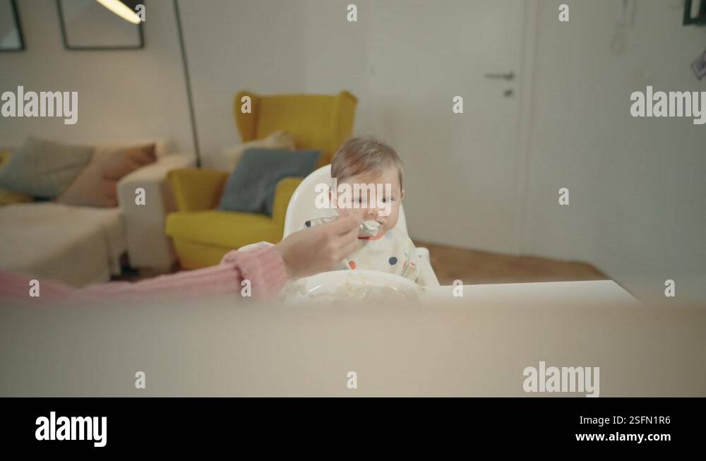 Baby girl being distracted with cartoon while eating. Common parenting ...