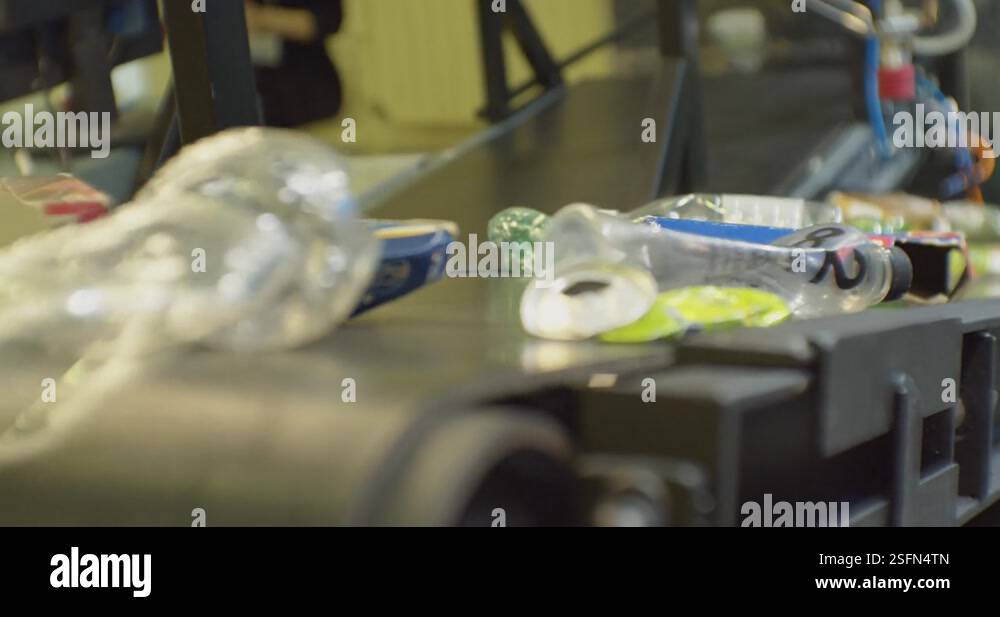 plastic bottles and paper packaging move along the conveyor of the ...